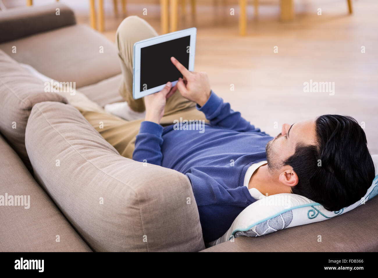 Man using tablet lying on the couch Stock Photo - Alamy