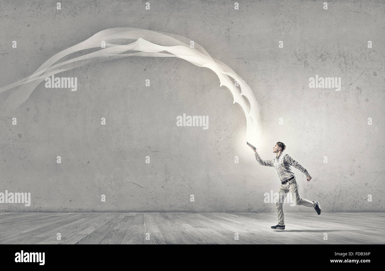 Full length of student running with book in hand Stock Photo - Alamy