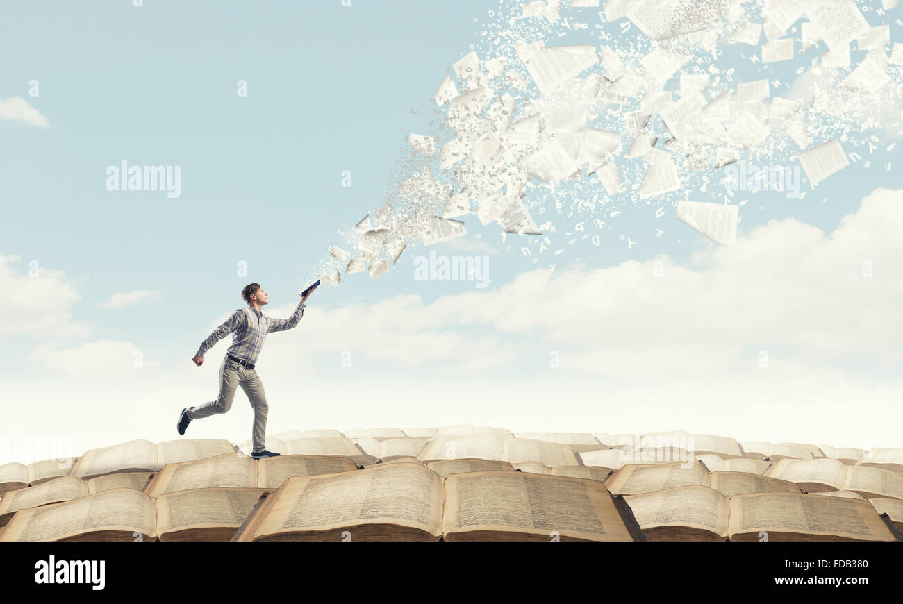 Full length of student running with book in hand Stock Photo - Alamy