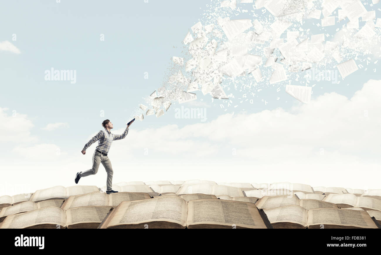 Full length of student running with book in hand Stock Photo - Alamy