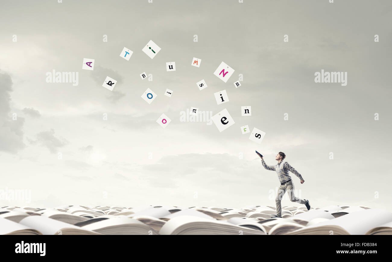 Full length of student running with book in hand Stock Photo - Alamy