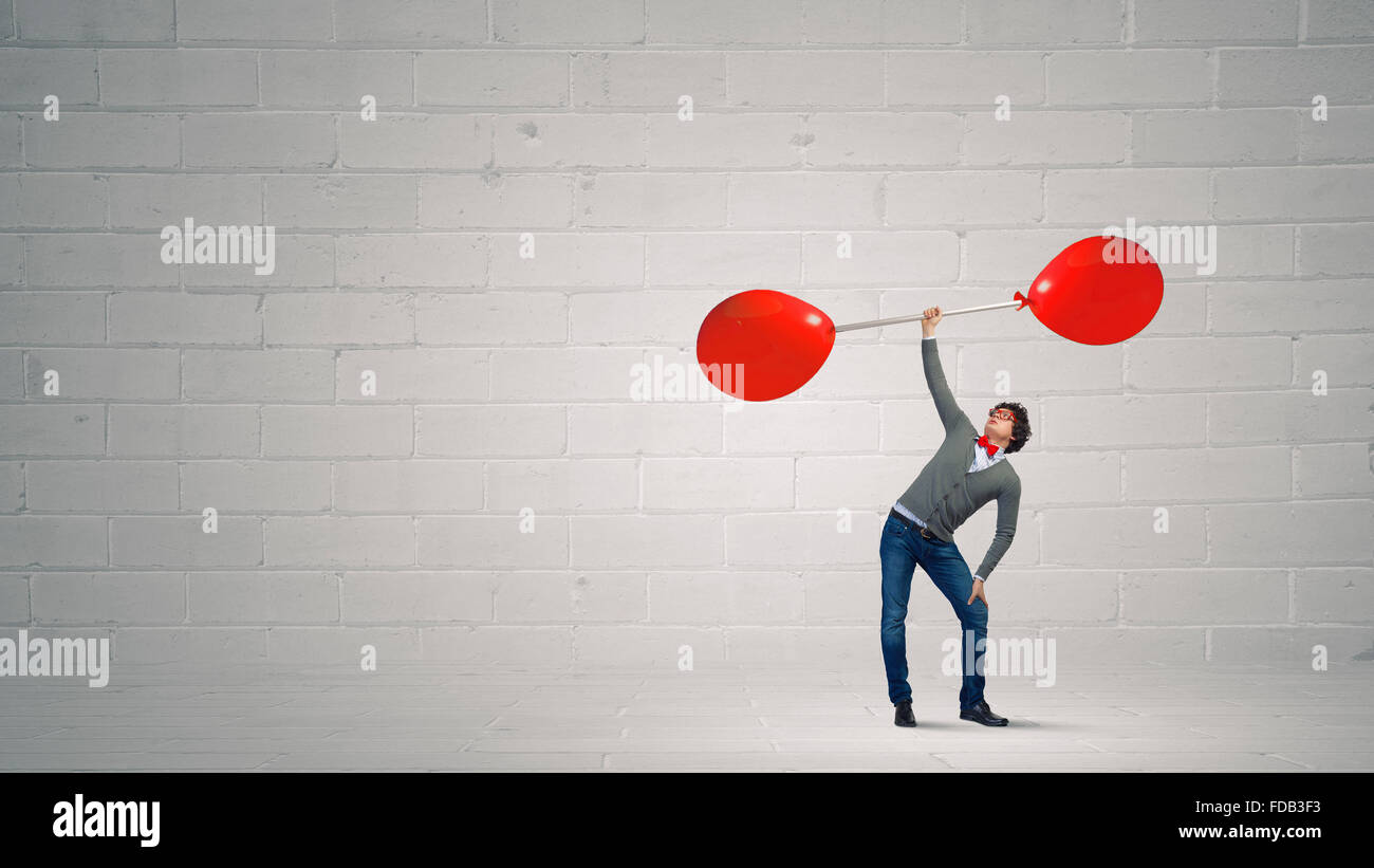 Confident guy lifting above head barbell with balloons Stock Photo - Alamy