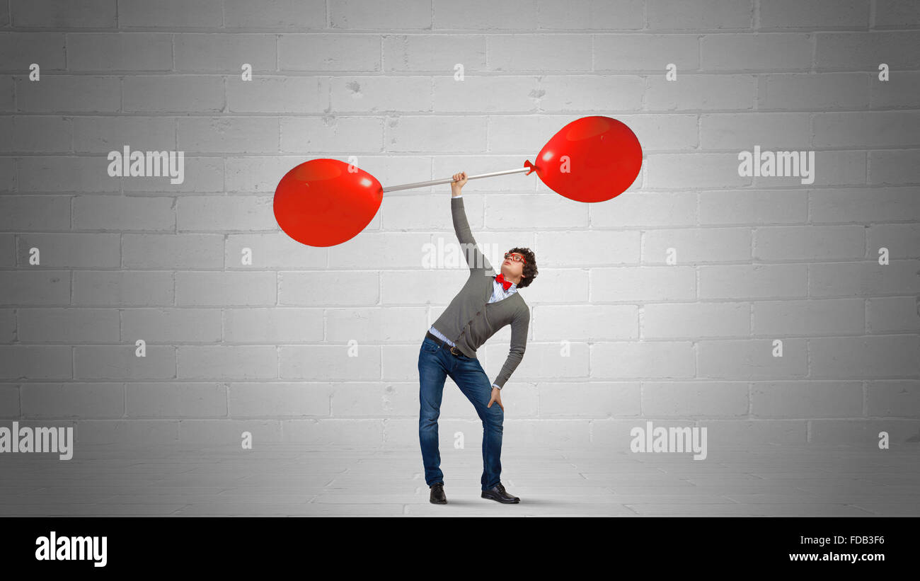 Confident guy lifting above head barbell with balloons Stock Photo - Alamy