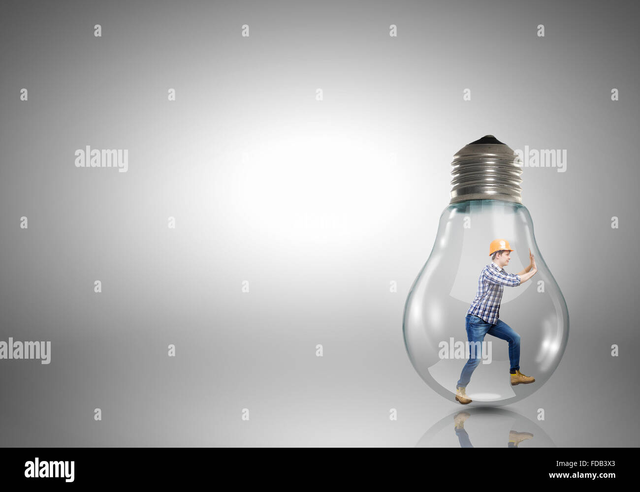 Builder man inside light bulb trying to get out Stock Photo - Alamy