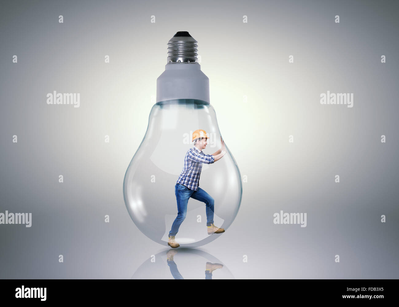 Builder man inside light bulb trying to get out Stock Photo - Alamy