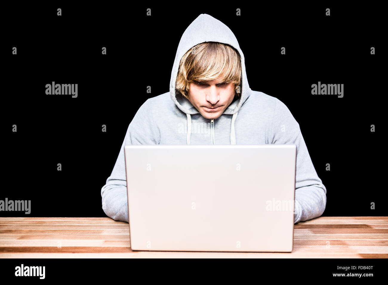 Man in hood jacket hacking a laptop Stock Photo - Alamy