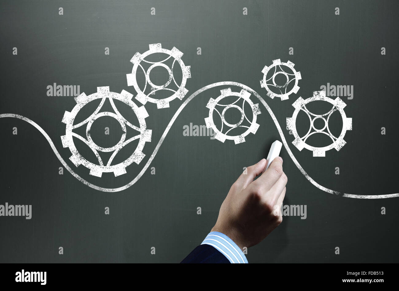 Businessman hand drawing with chalk gears mechanism as teamwork concept ...