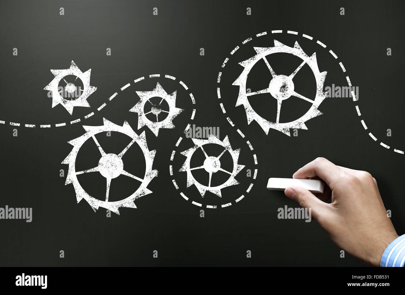 Businessman hand drawing with chalk gears mechanism as teamwork concept ...