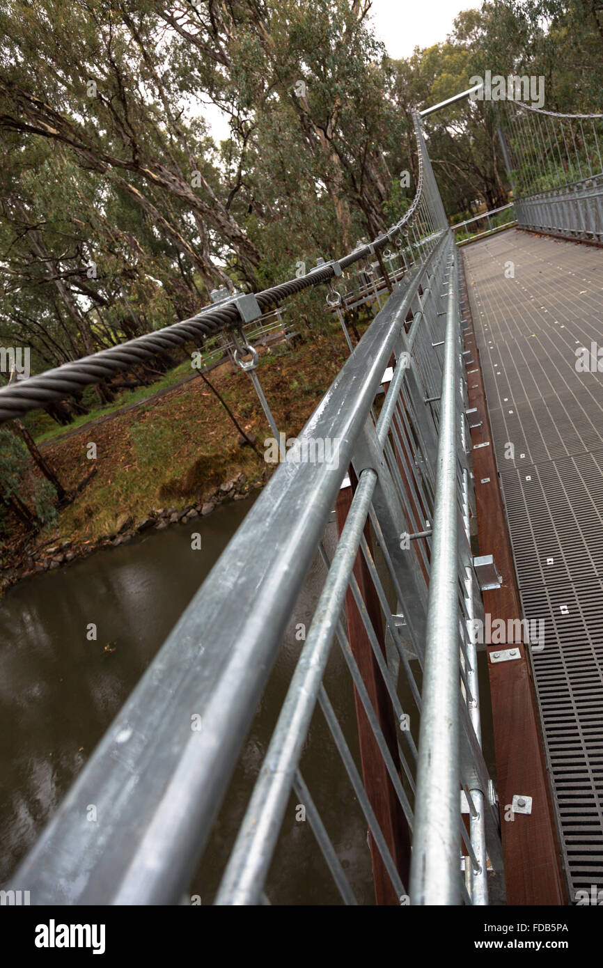 A large steel suspension foot bridge over a river nestled in the ...