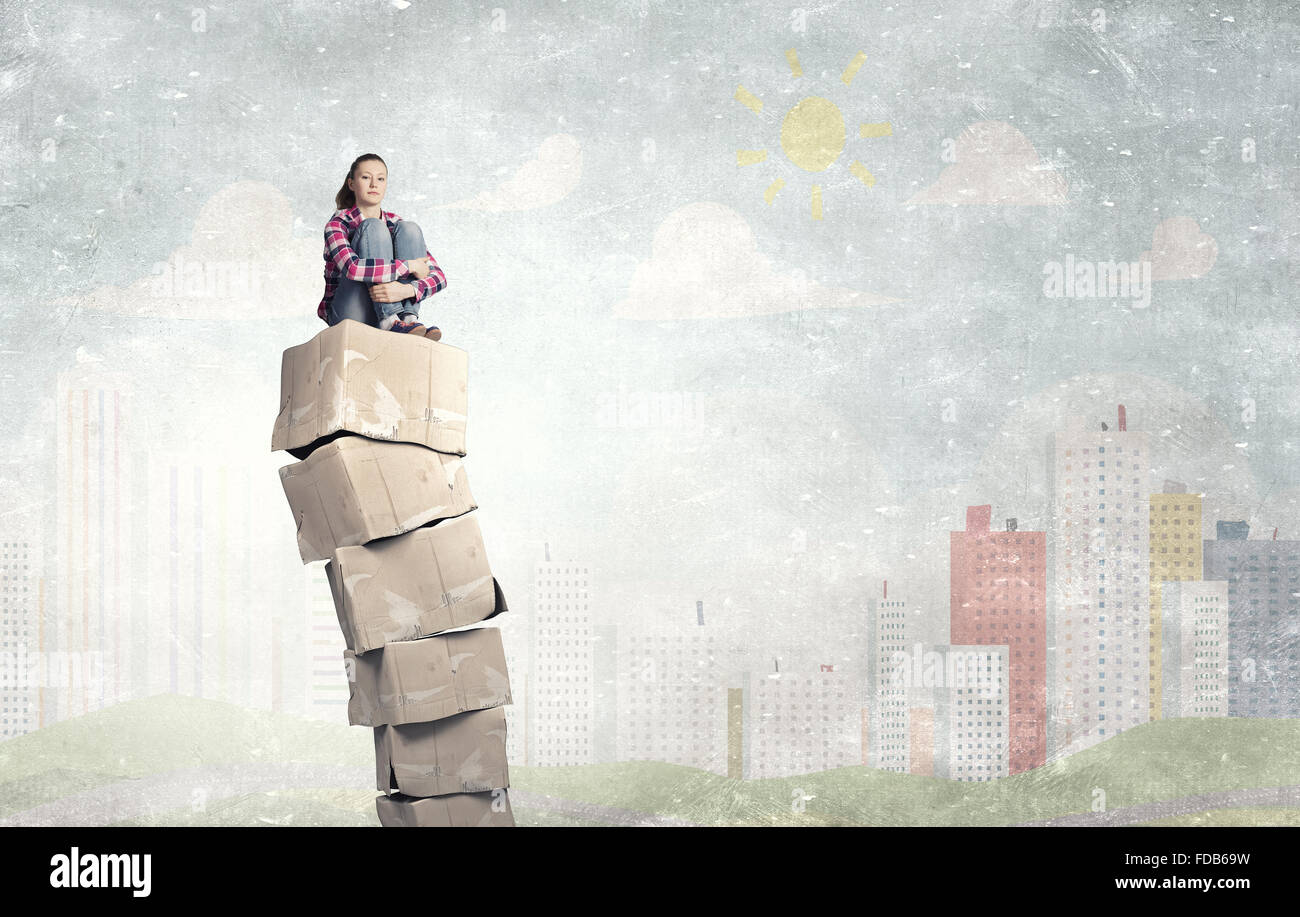Smiling young woman sitting on stack of carton boxes Stock Photo - Alamy