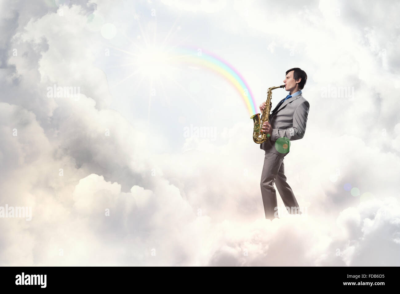 Young man playing saxophone on sky background Stock Photo - Alamy