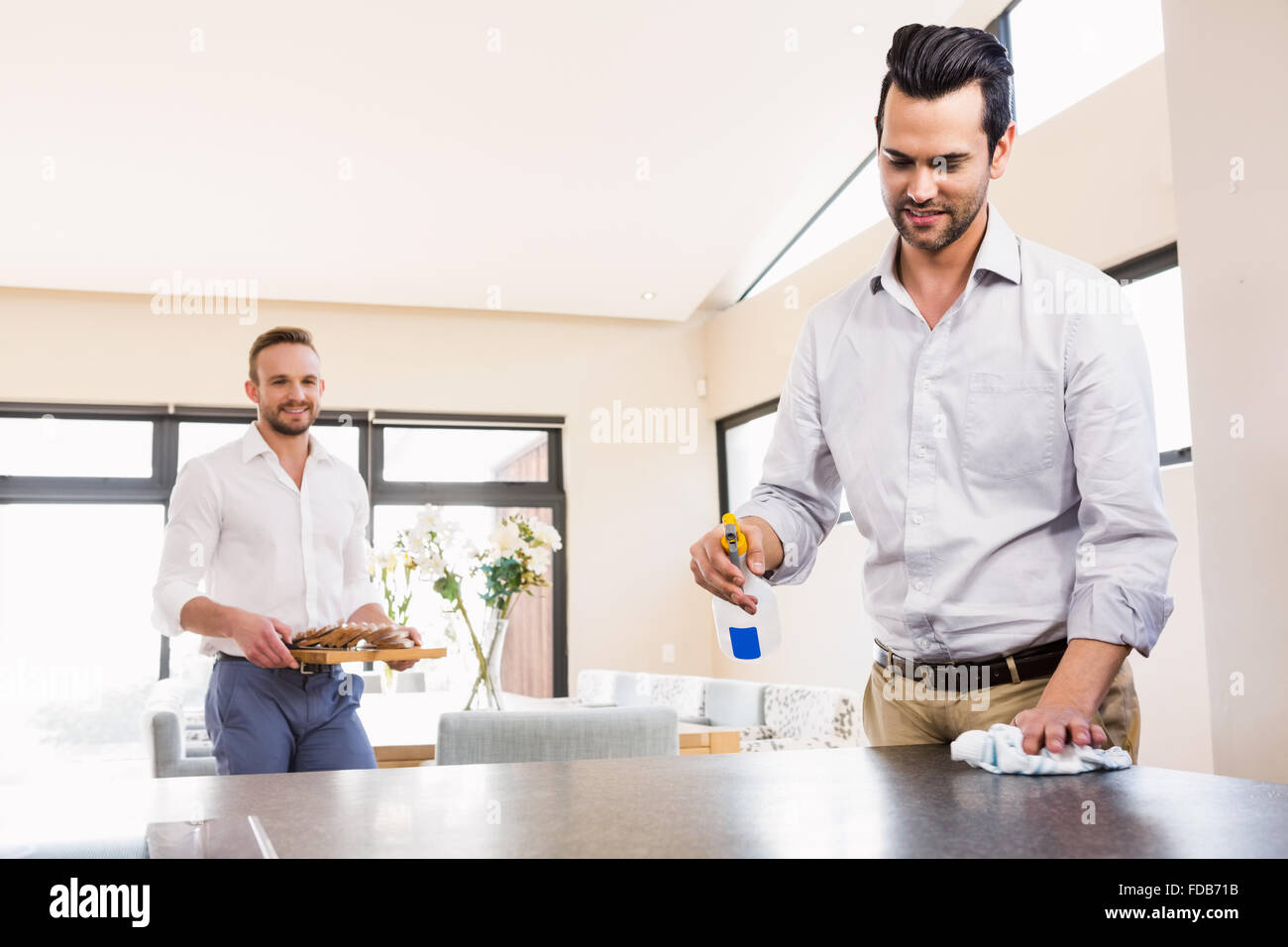 Smiling gay couple cleaning living room Stock Photo - Alamy