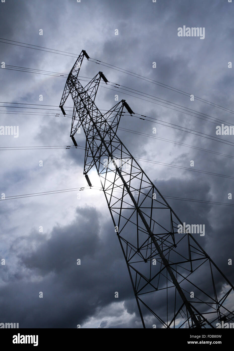 Pylon or transmission tower silhouetted against a stormy sky. Burst of ...