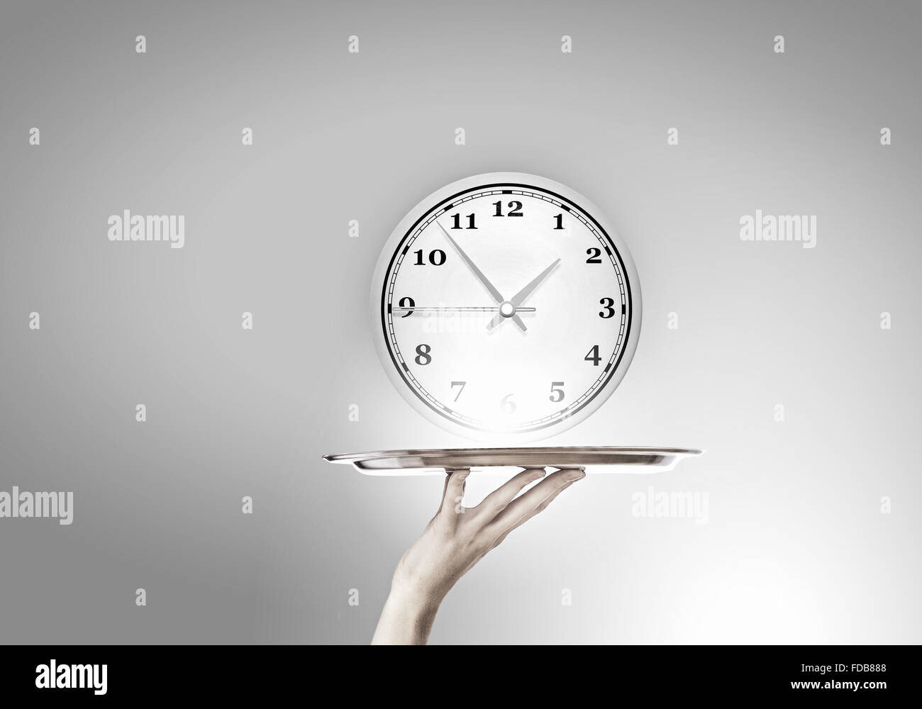 Waiter holding silver platter with white alarm clock Stock Photo - Alamy