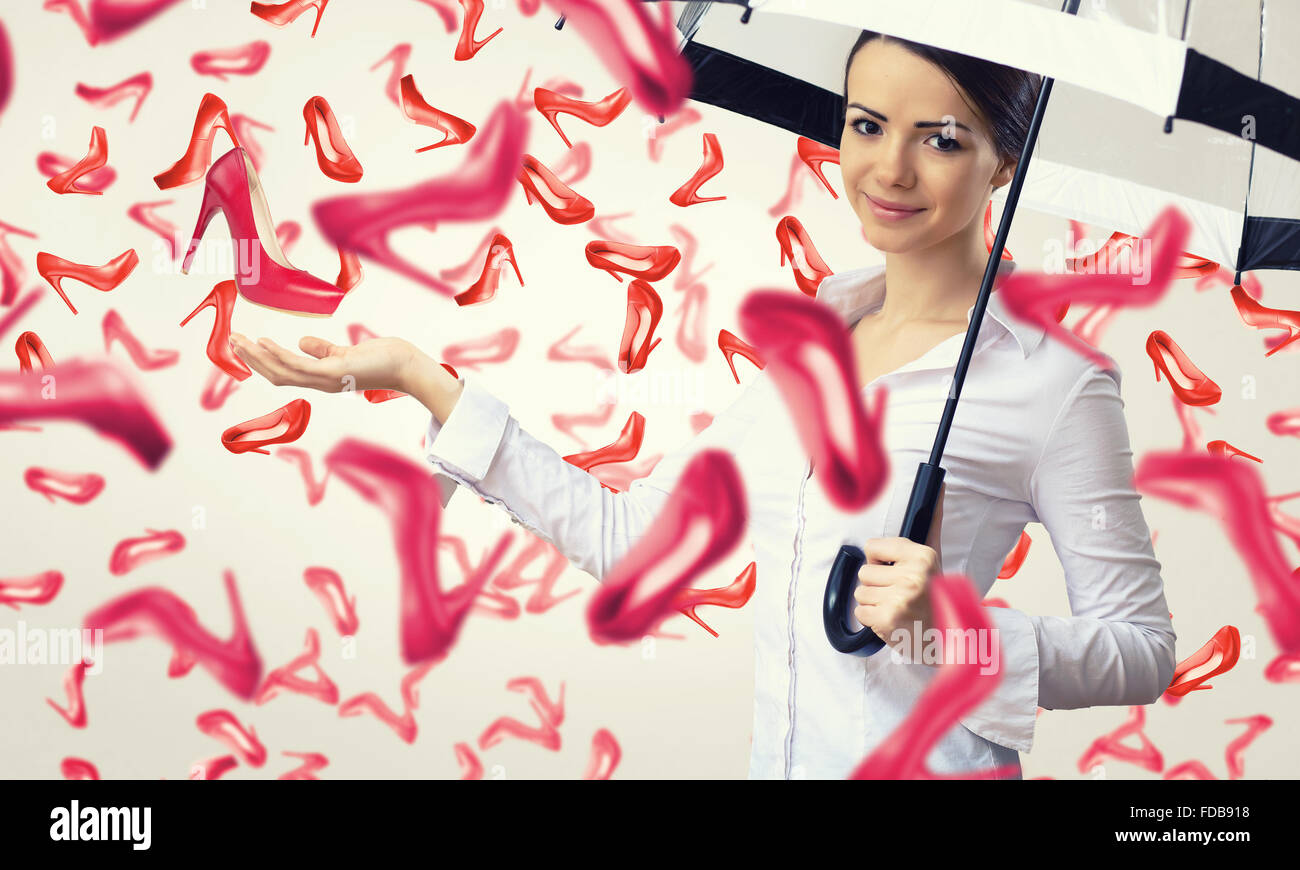 Beautiful young woman with umbrella and falling shoes Stock Photo - Alamy
