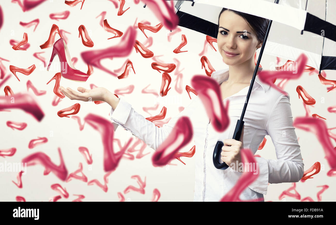 Beautiful young woman with umbrella and falling shoes Stock Photo - Alamy