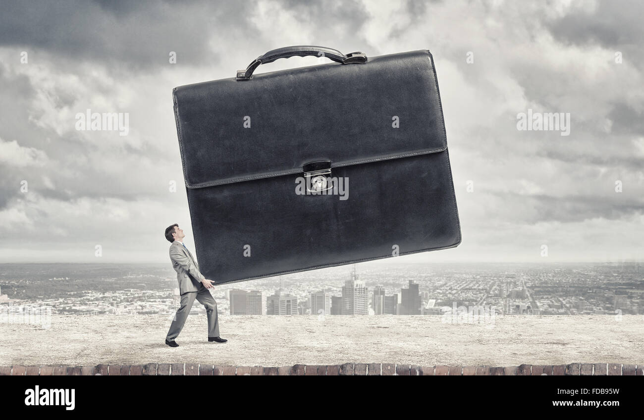 Young determined businessman carrying big heavy suitcase Stock Photo ...