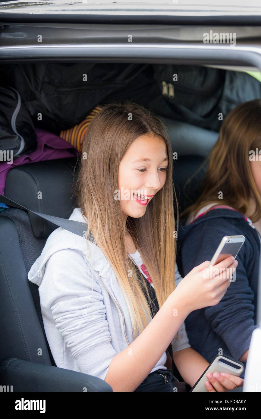 MODEL RELEASED. Teenage girl using smartphone in a car, smiling Stock ...