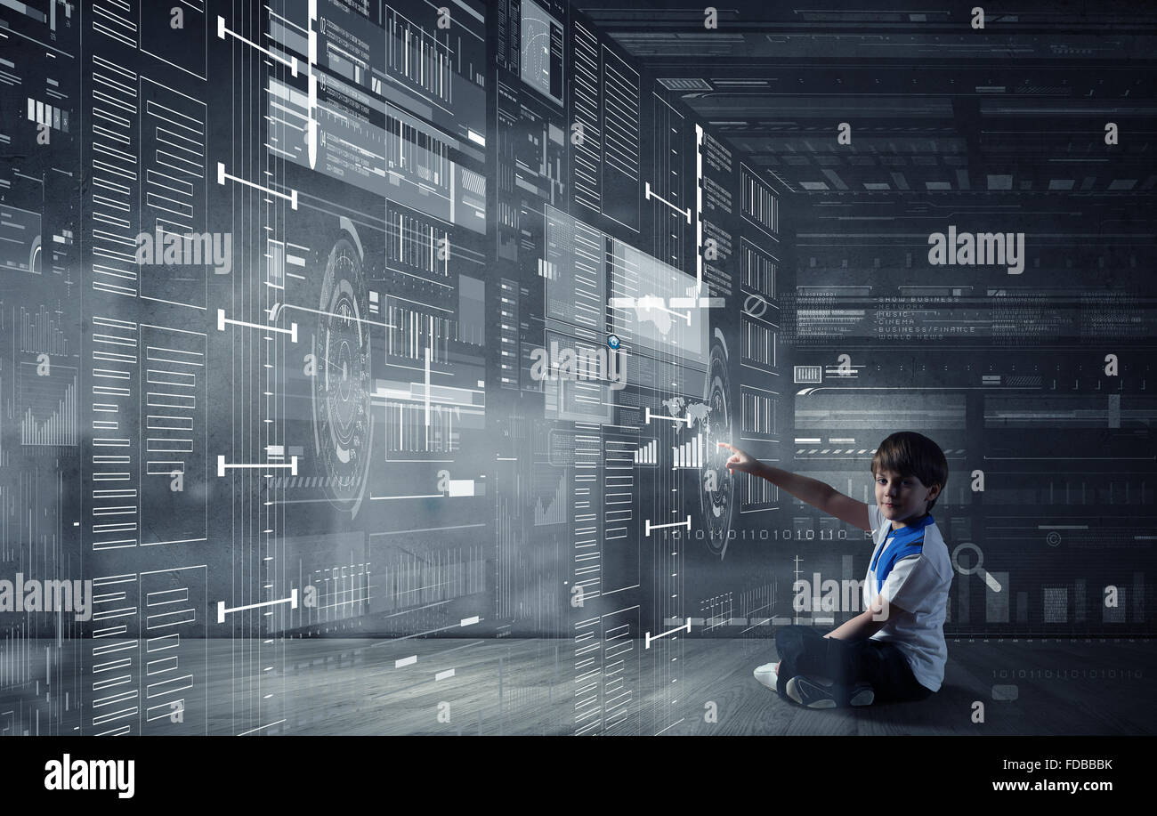 Cute school boy sitting on floor and touching digital screen with ...