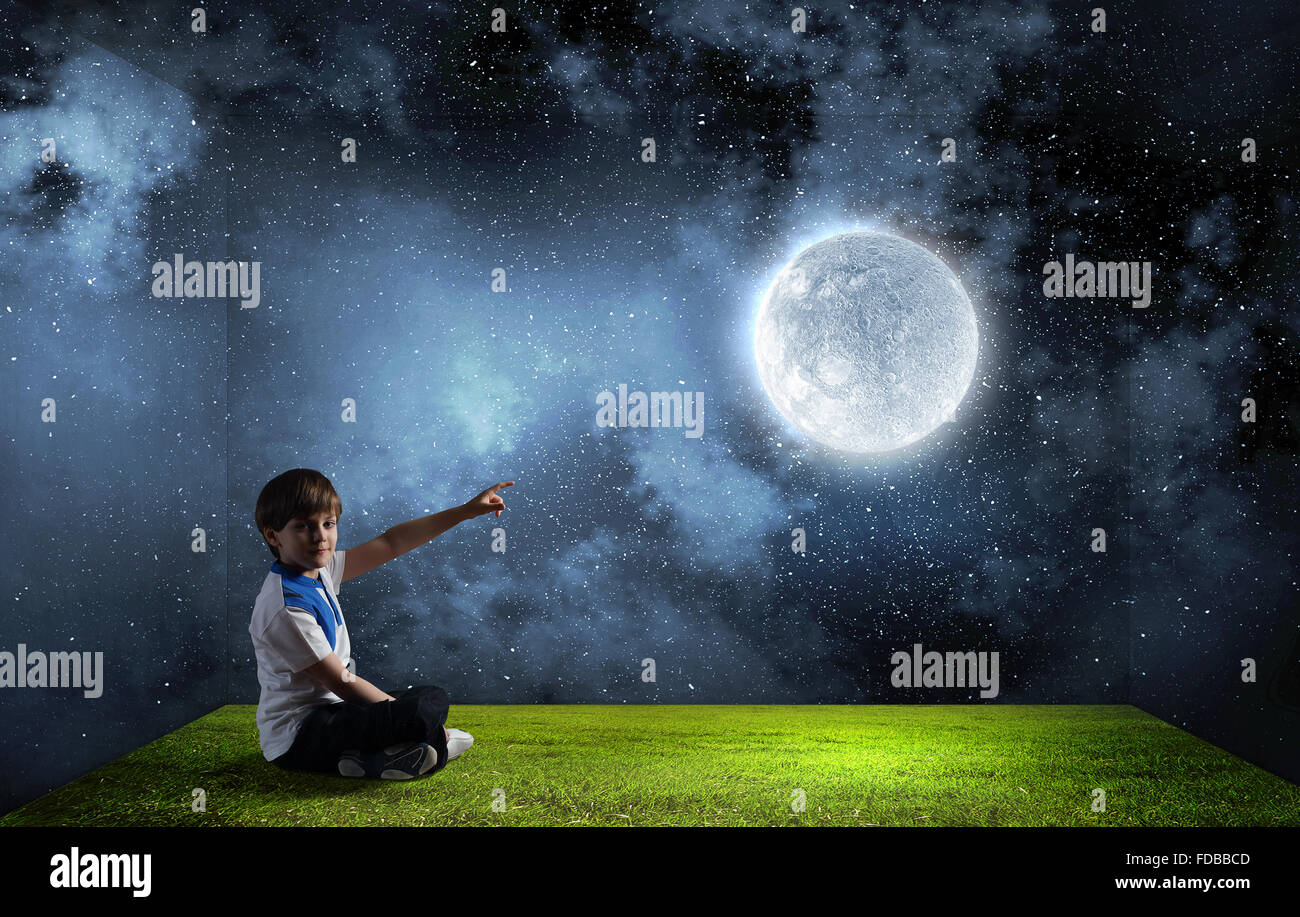 Cute school boy sitting on floor and touching moon with finger Stock ...