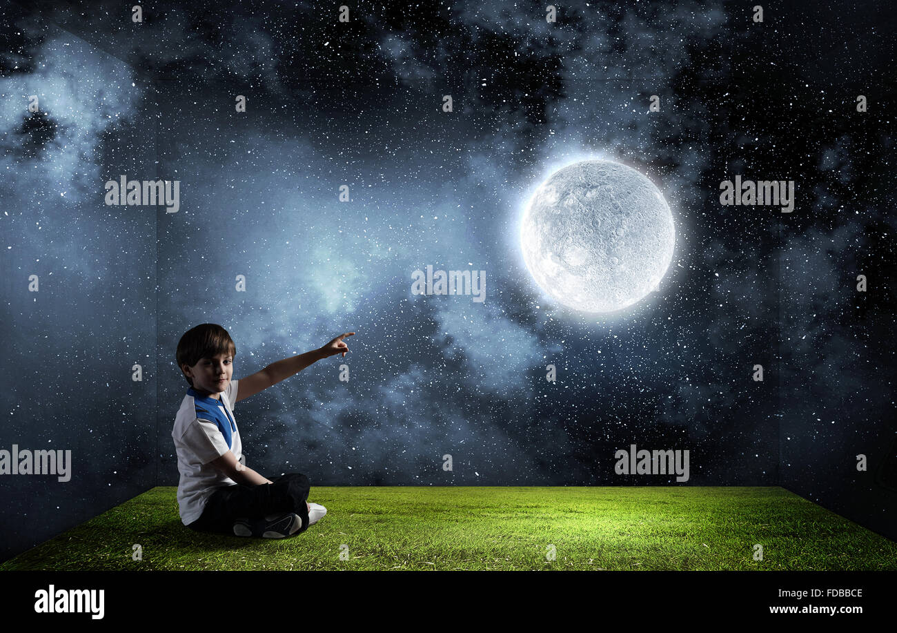 Cute school boy sitting on floor and touching moon with finger Stock ...