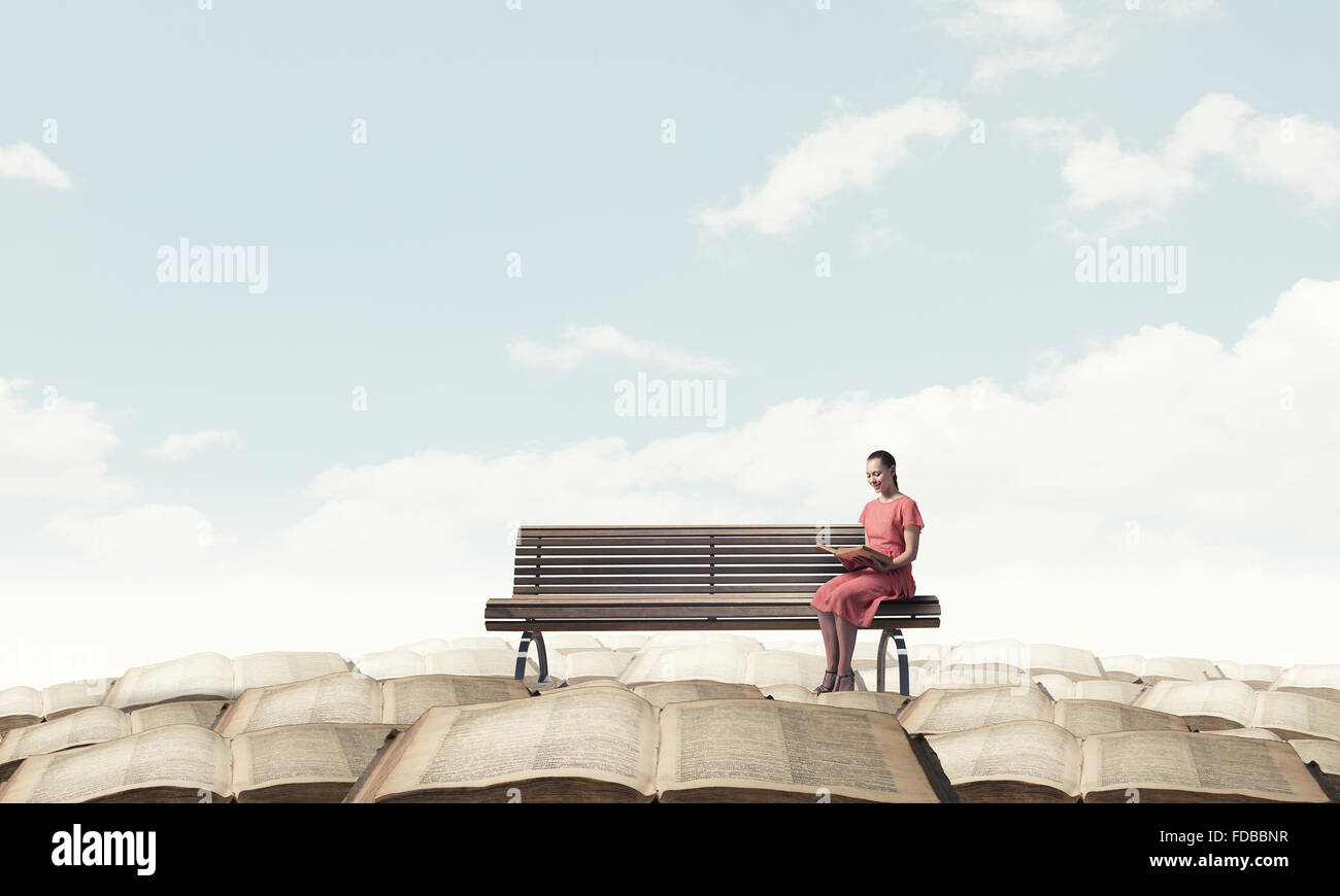 Young woman sitting on bench and reading book Stock Photo - Alamy