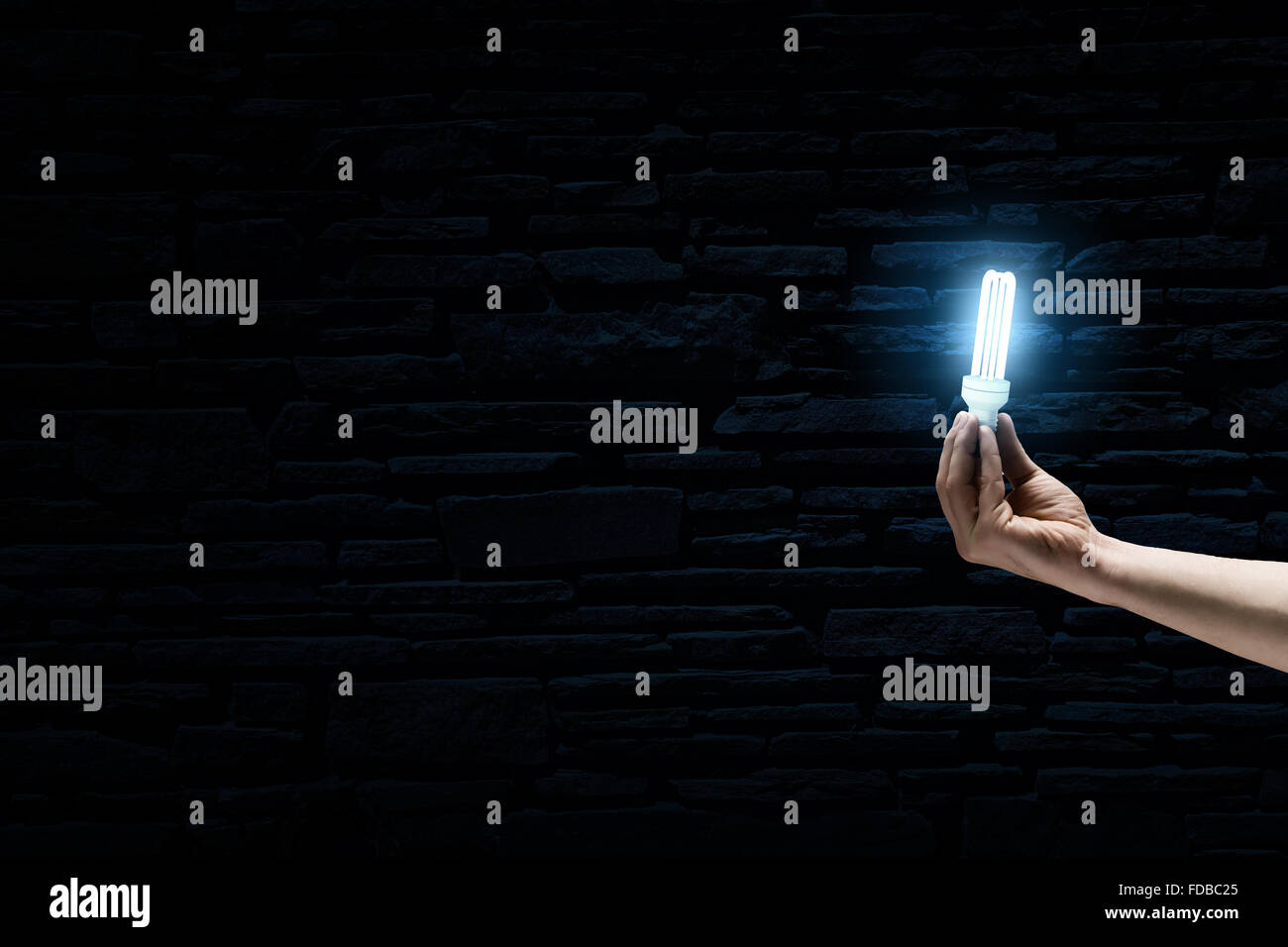 Male hand on dark background showing glass light bulb Stock Photo - Alamy