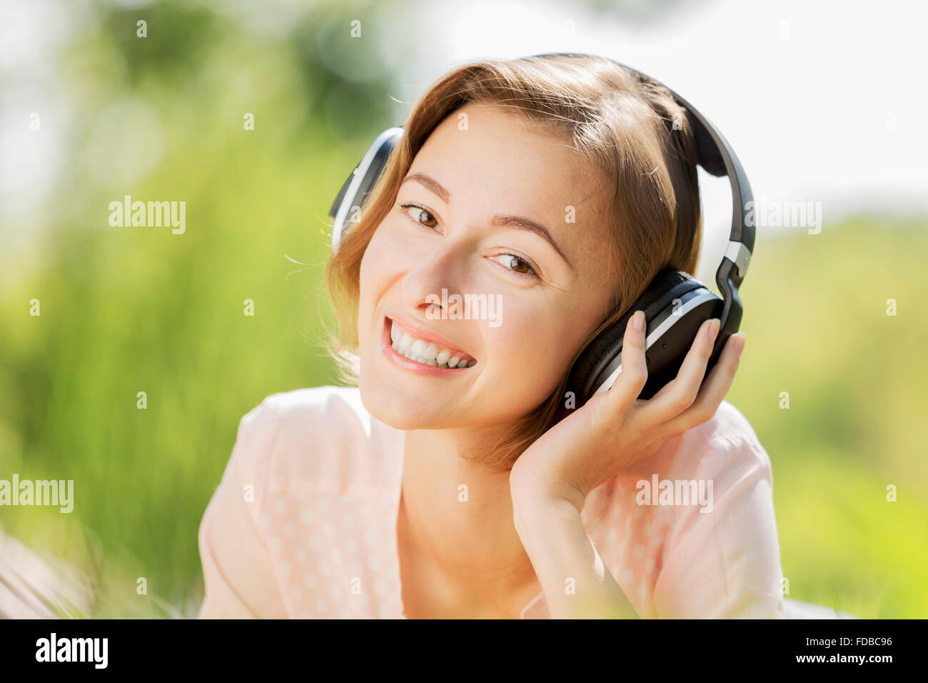 Young pretty lady in park listening to music Stock Photo - Alamy