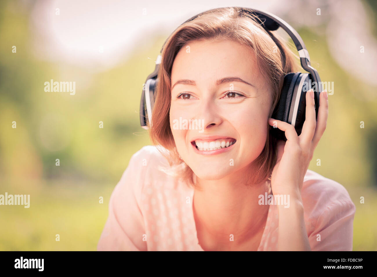 Young pretty lady in park listening to music Stock Photo - Alamy