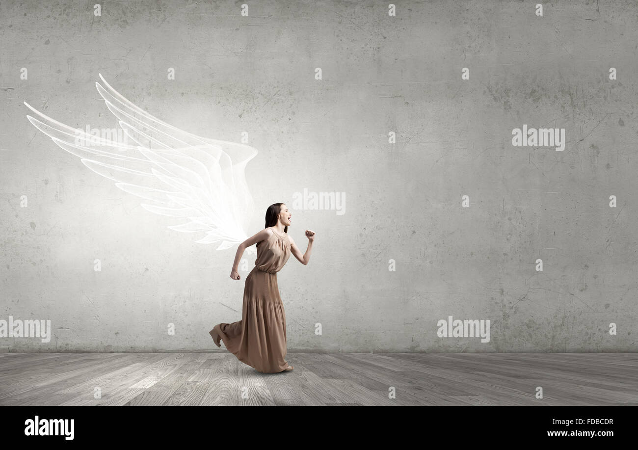 Attractive woman running with angel wings behind back Stock Photo - Alamy