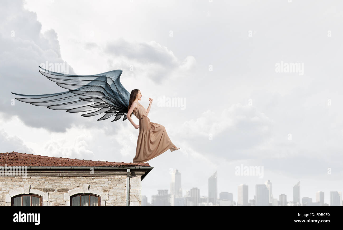 Attractive woman running with angel wings behind back Stock Photo - Alamy