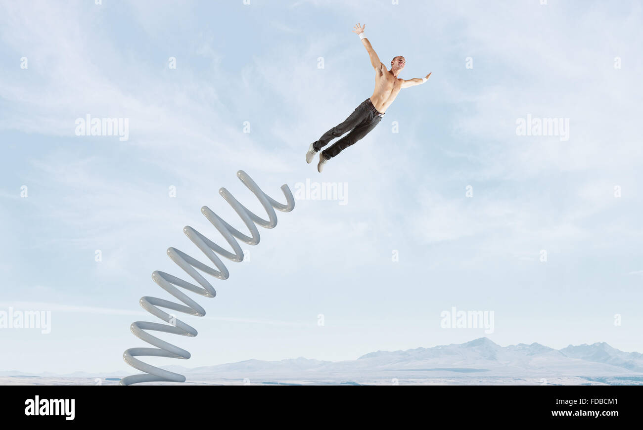 Young man jumping on spring and flying in air Stock Photo - Alamy