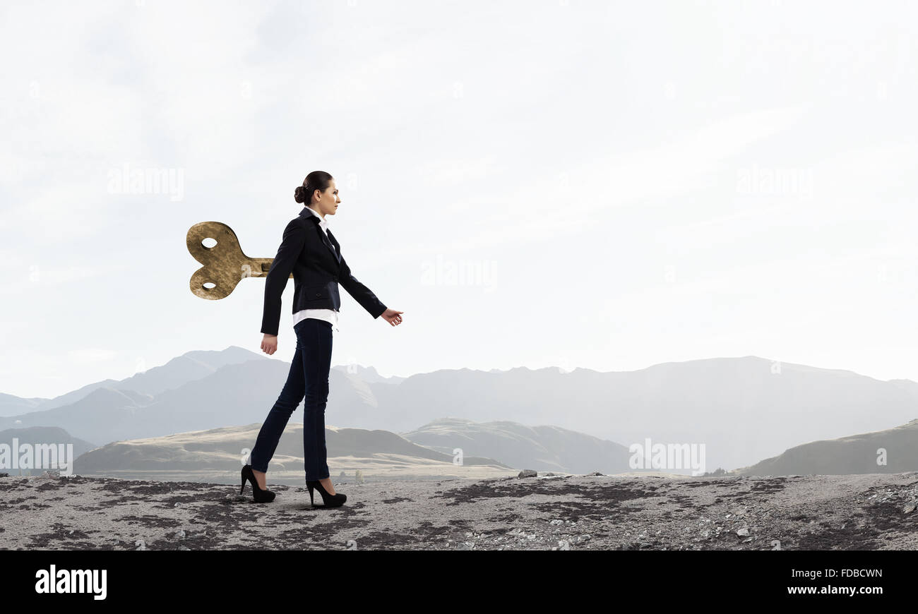 Young businesswoman walking with wind up key in his back Stock Photo ...
