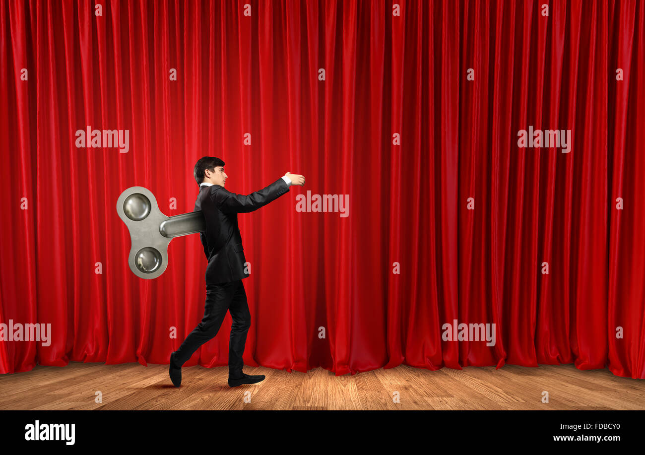 Young businessman walking with wind up key in his back Stock Photo - Alamy