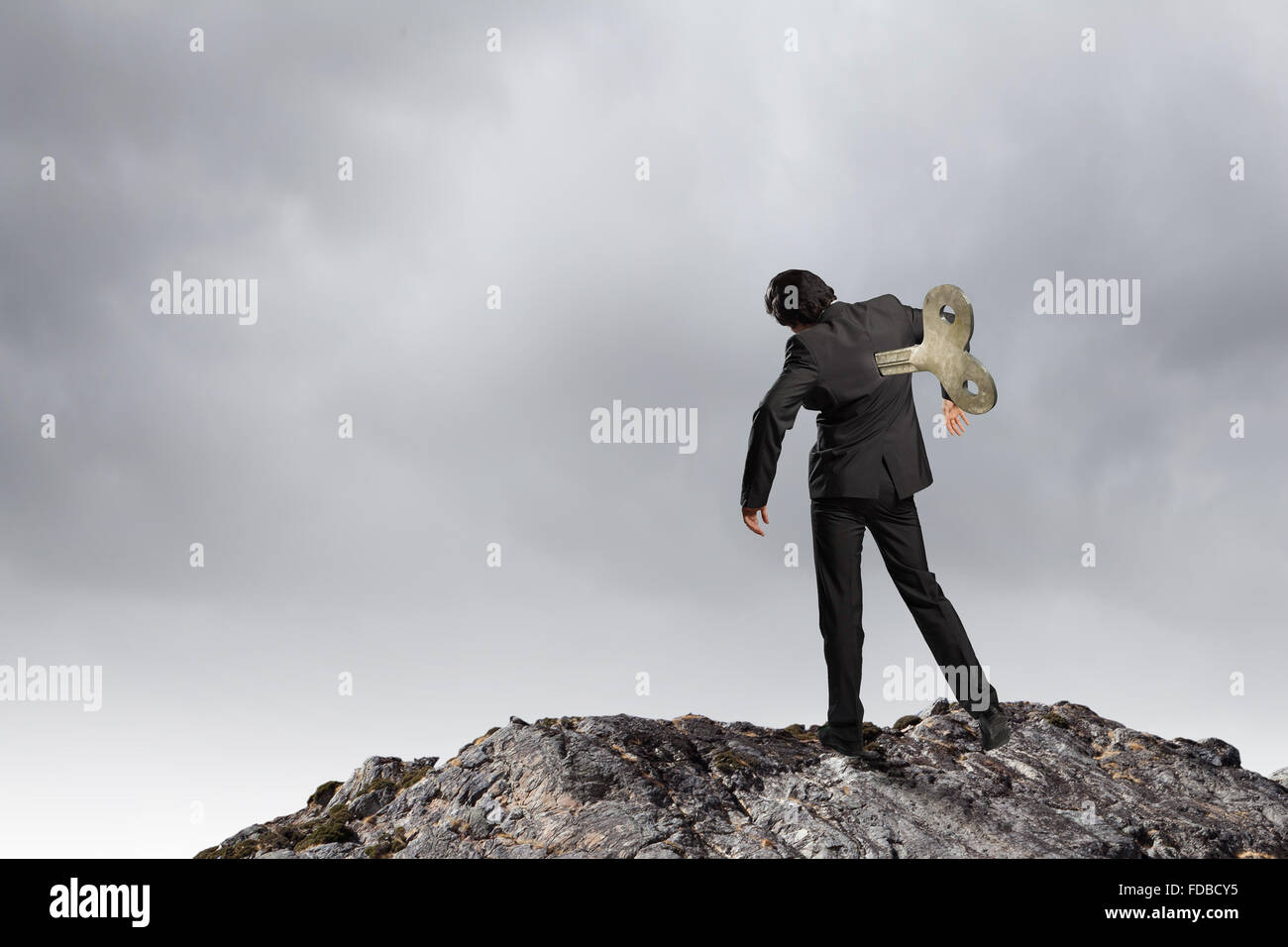 Young businessman walking with wind up key in his back Stock Photo - Alamy