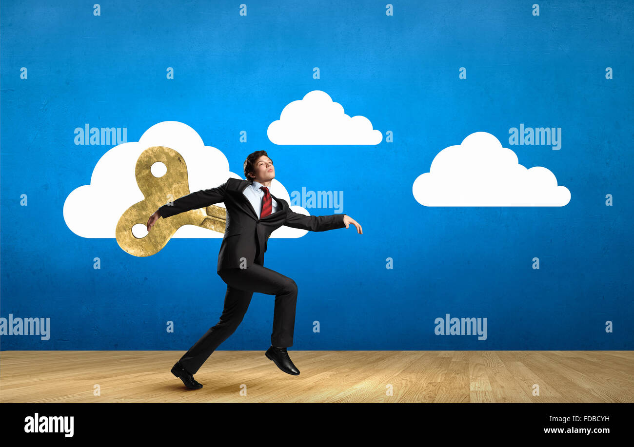 Young businessman walking with wind up key in his back Stock Photo - Alamy