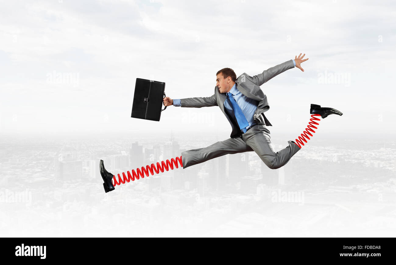 Businessman in suit jumping with big springs on feet Stock Photo - Alamy