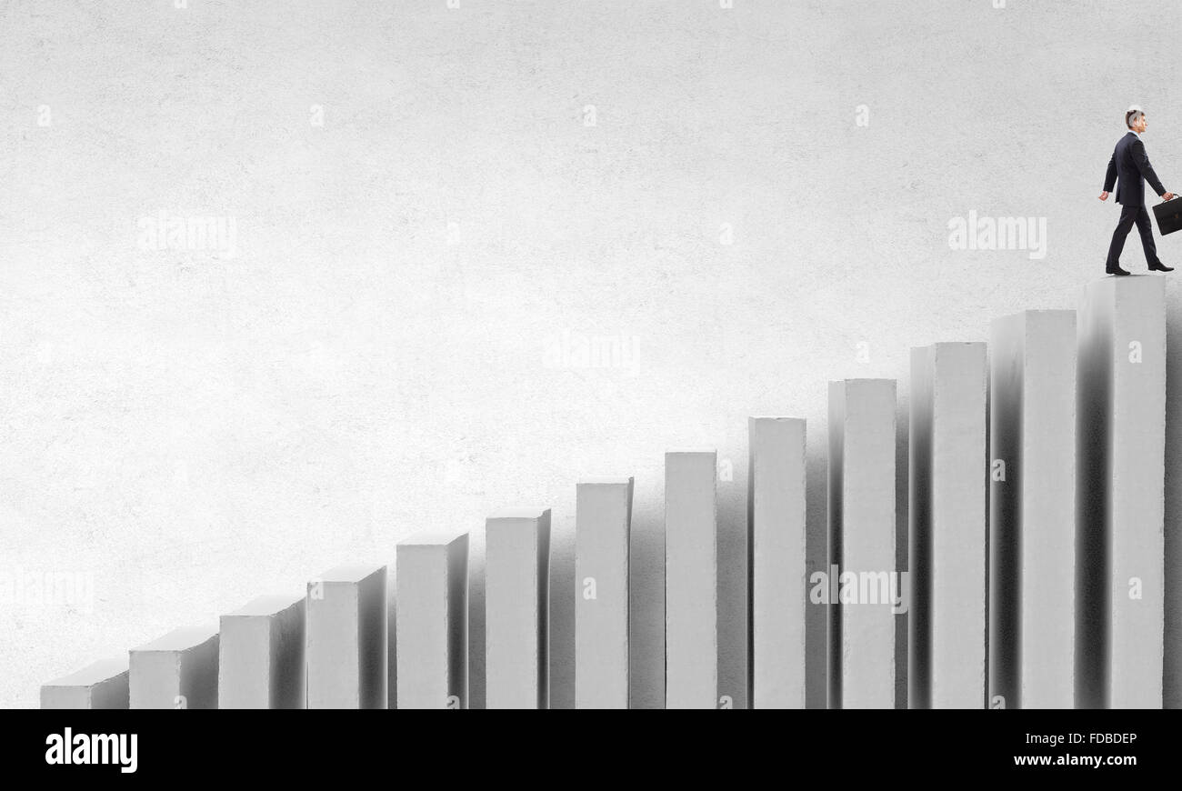 Young businessman walking up on growing graph representing success ...