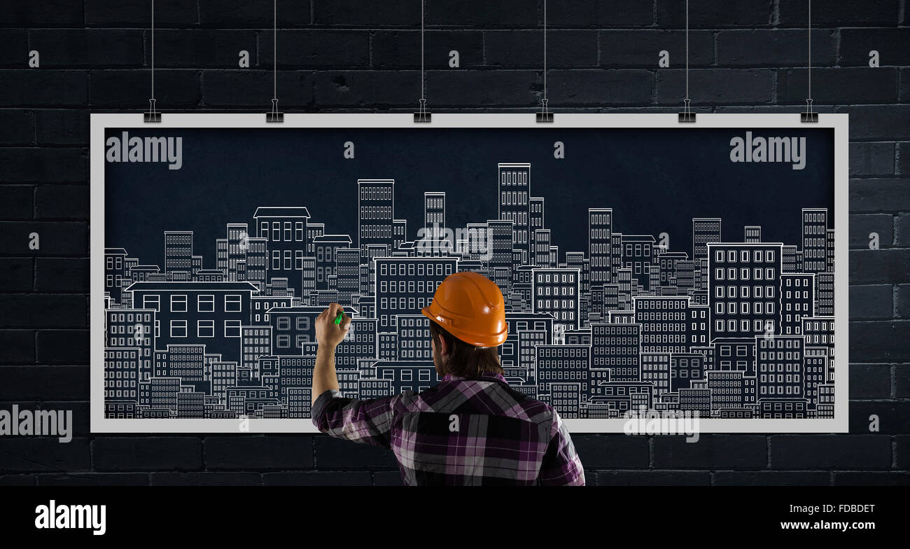 Rear view of man engineer in helmet drawing on chalkboard Stock Photo ...