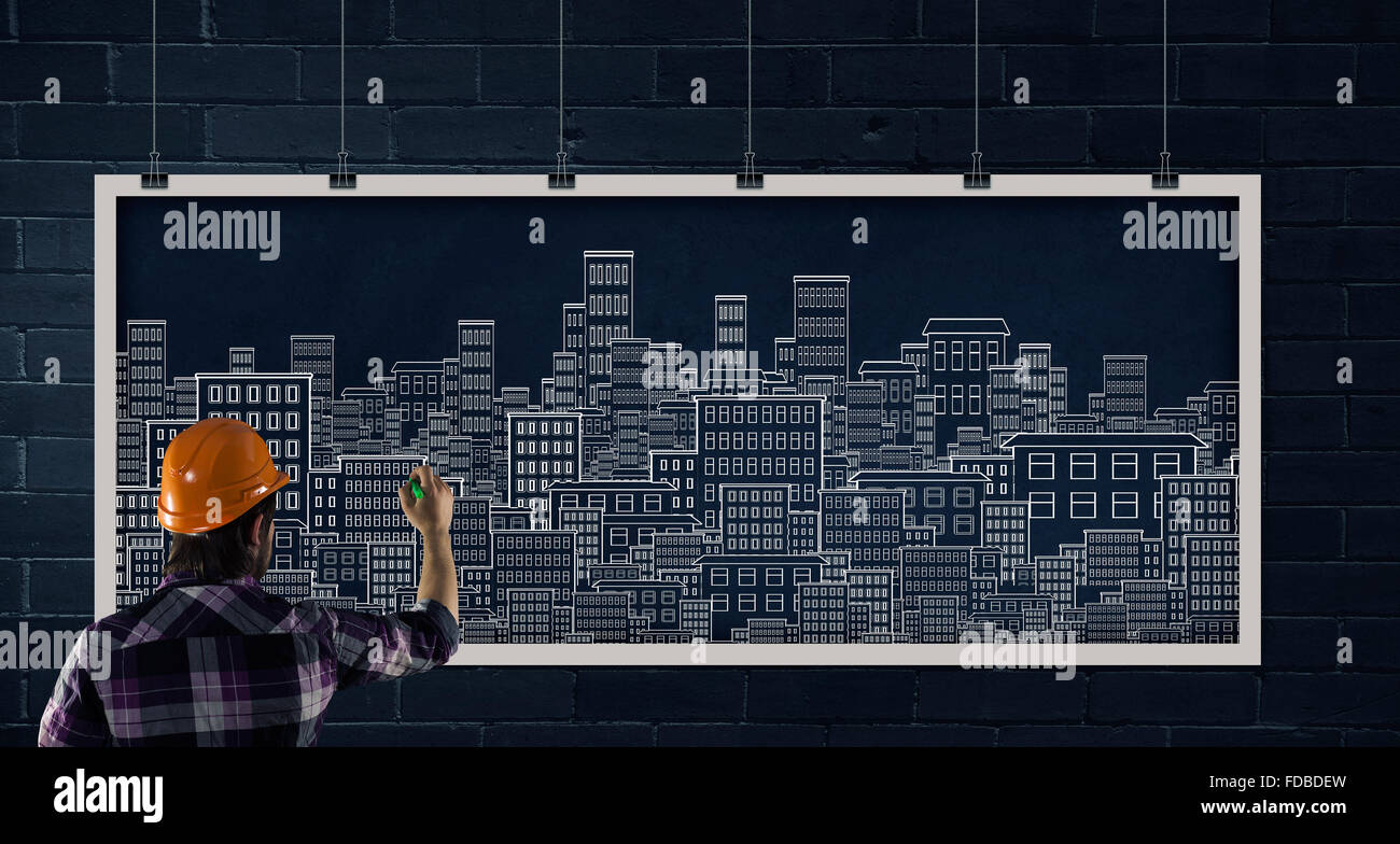 Rear view of man engineer in helmet drawing on chalkboard Stock Photo ...