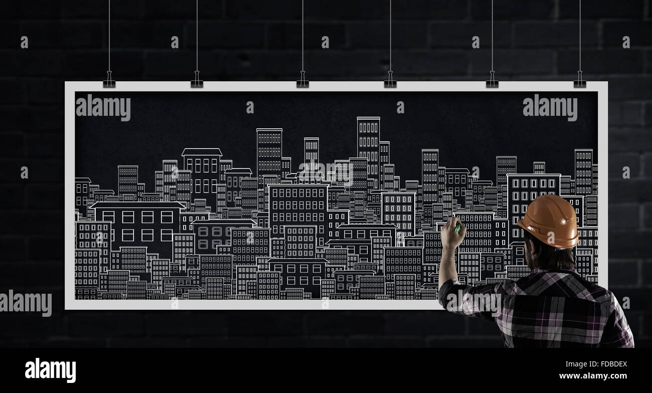 Rear view of man engineer in helmet drawing on chalkboard Stock Photo ...