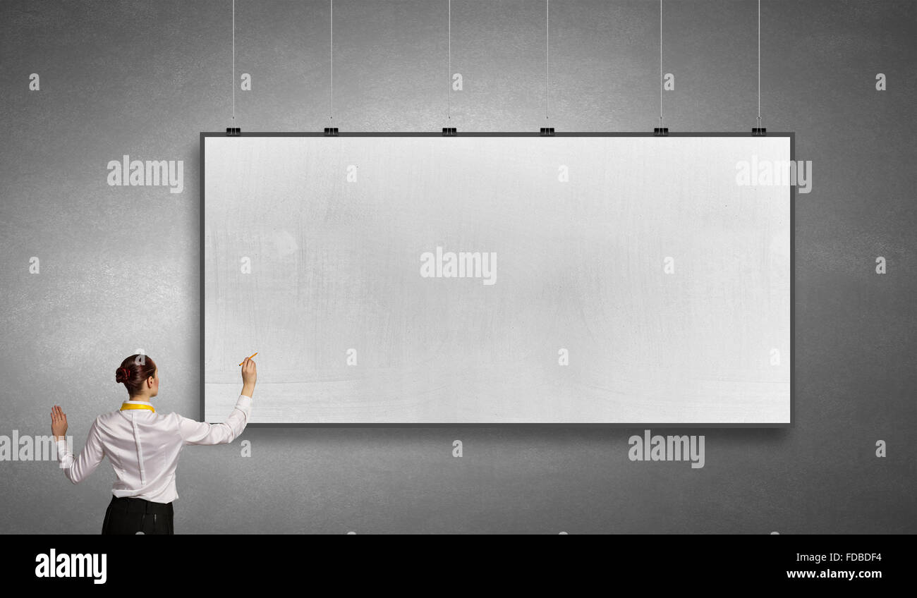 Rear view of businesswoman drawing on white blank banner on wall Stock ...