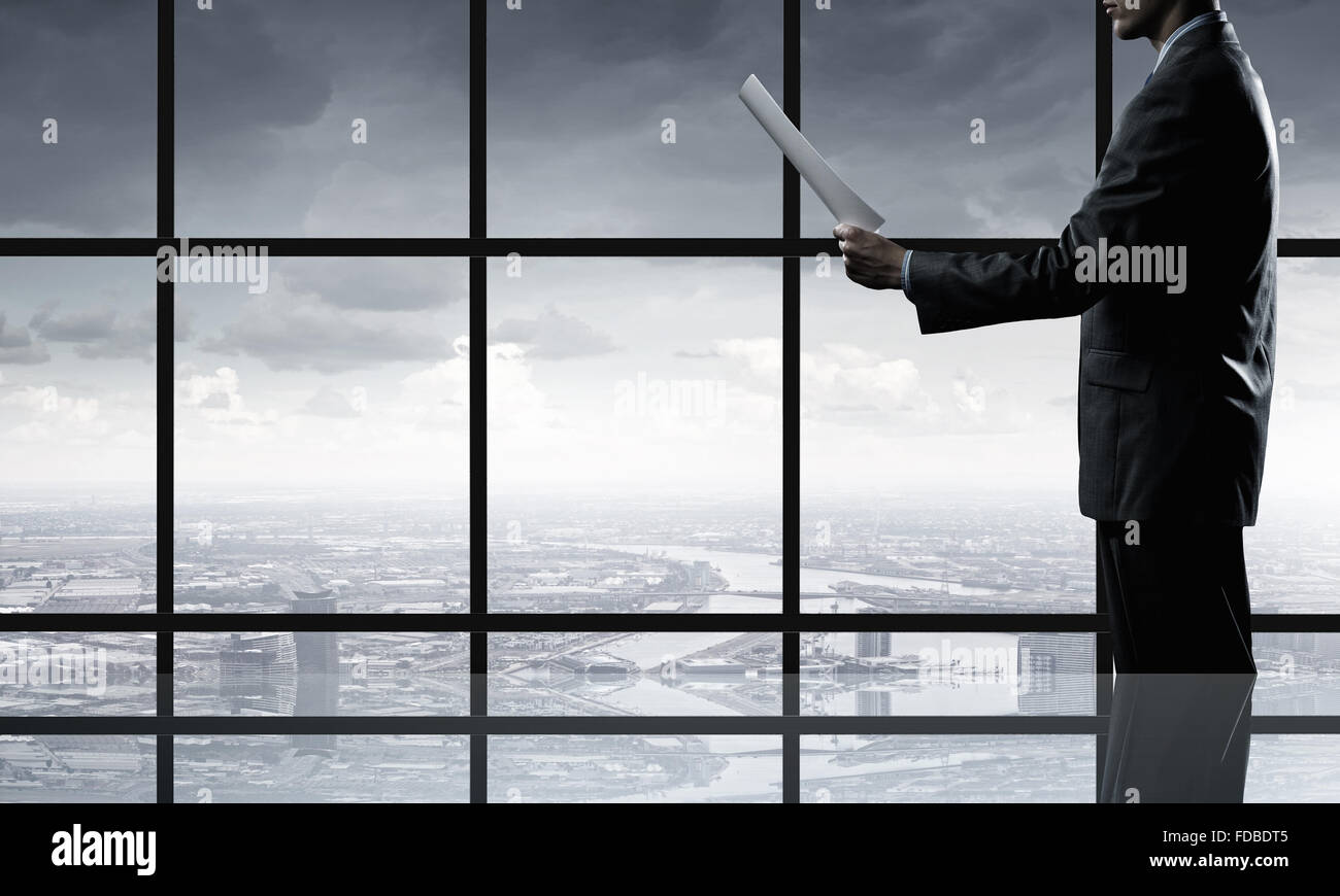Businessman looking in papers against office window Stock Photo - Alamy