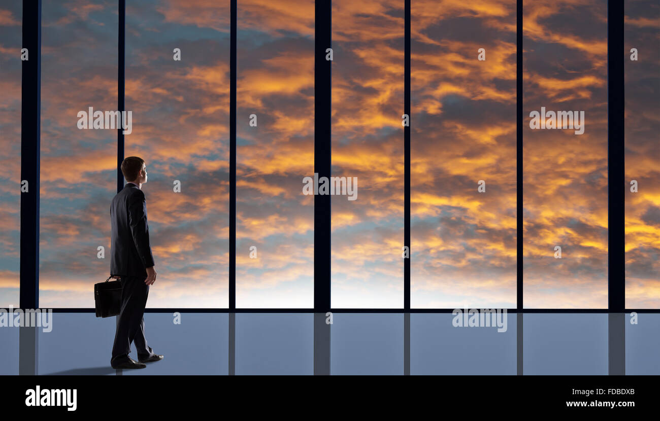 Back view of businessman looking on sunrise in office window Stock ...