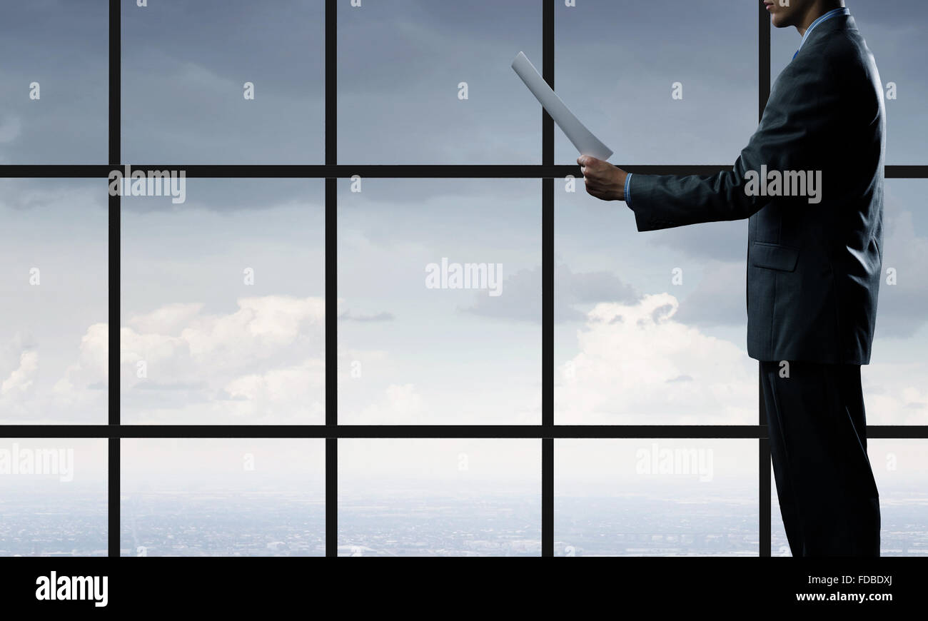 Businessman looking in papers against office window Stock Photo - Alamy