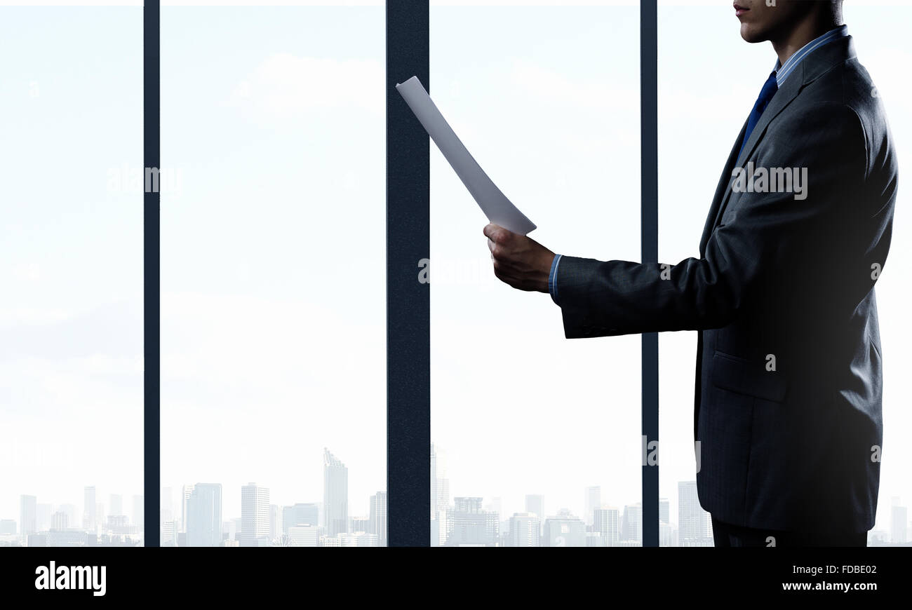 Businessman looking in papers against office window Stock Photo - Alamy