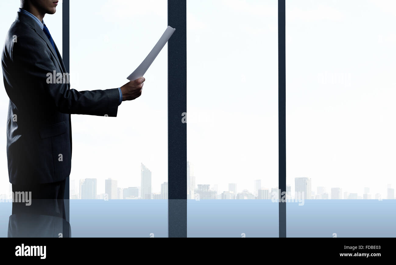 Businessman looking in papers against office window Stock Photo - Alamy