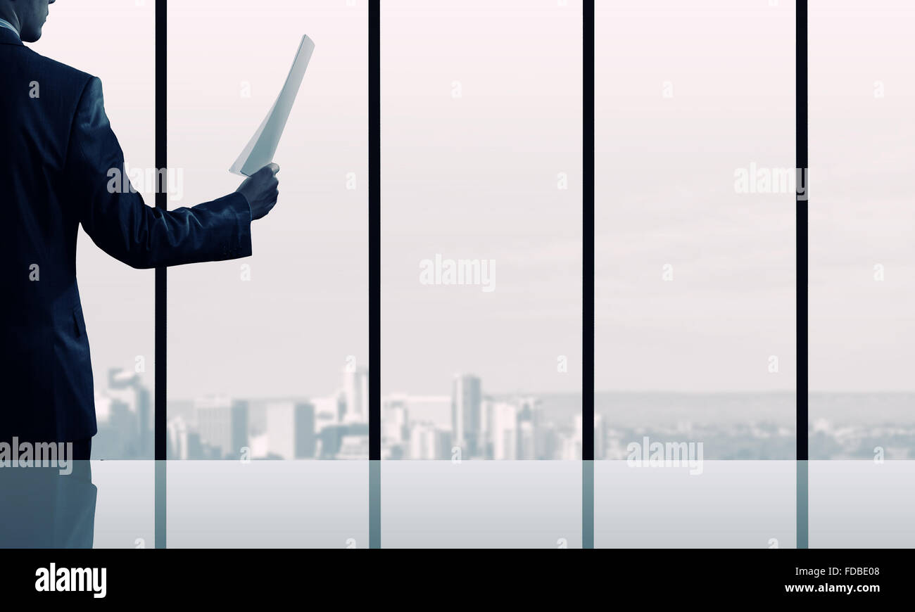 Businessman looking in papers against office window Stock Photo - Alamy
