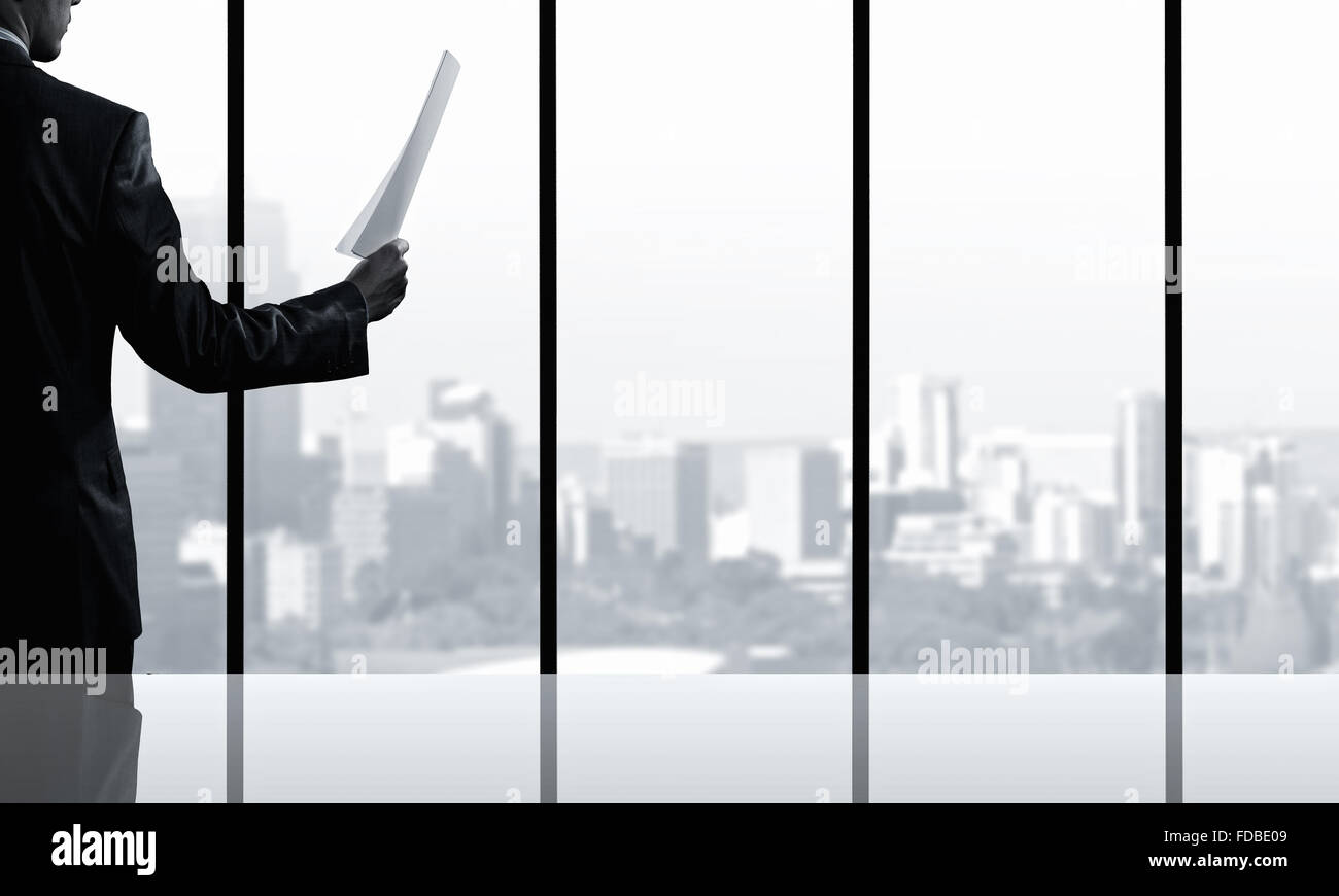 Businessman looking in papers against office window Stock Photo - Alamy