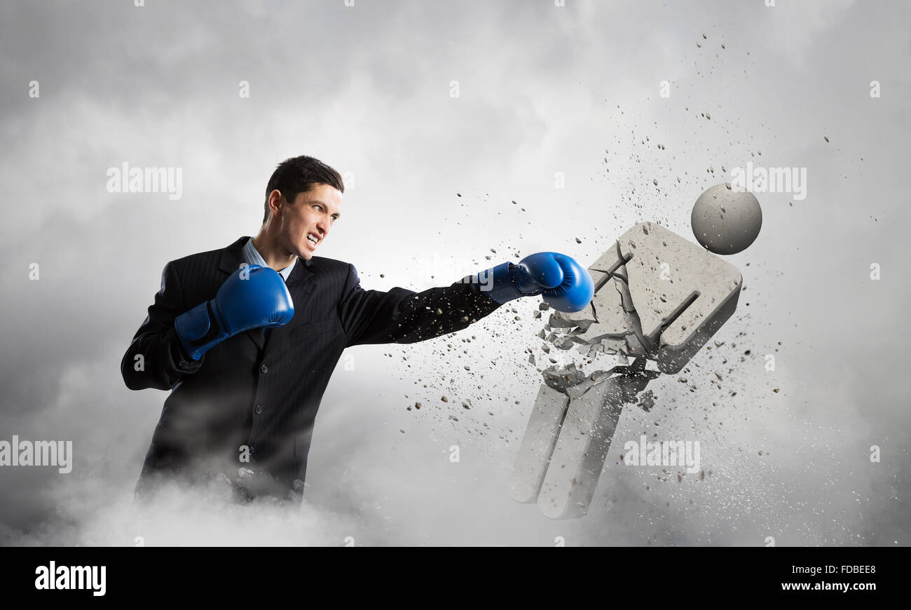 Young businessman in blue boxing gloves on cement background Stock ...